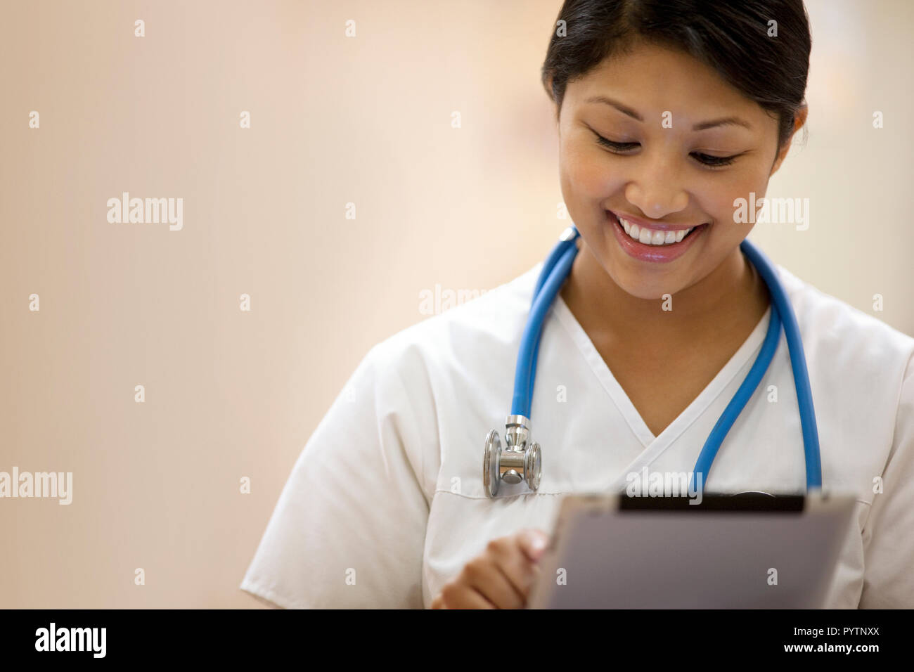 Portrait of young female nurse writing on a clipboard Stock Photo - Alamy