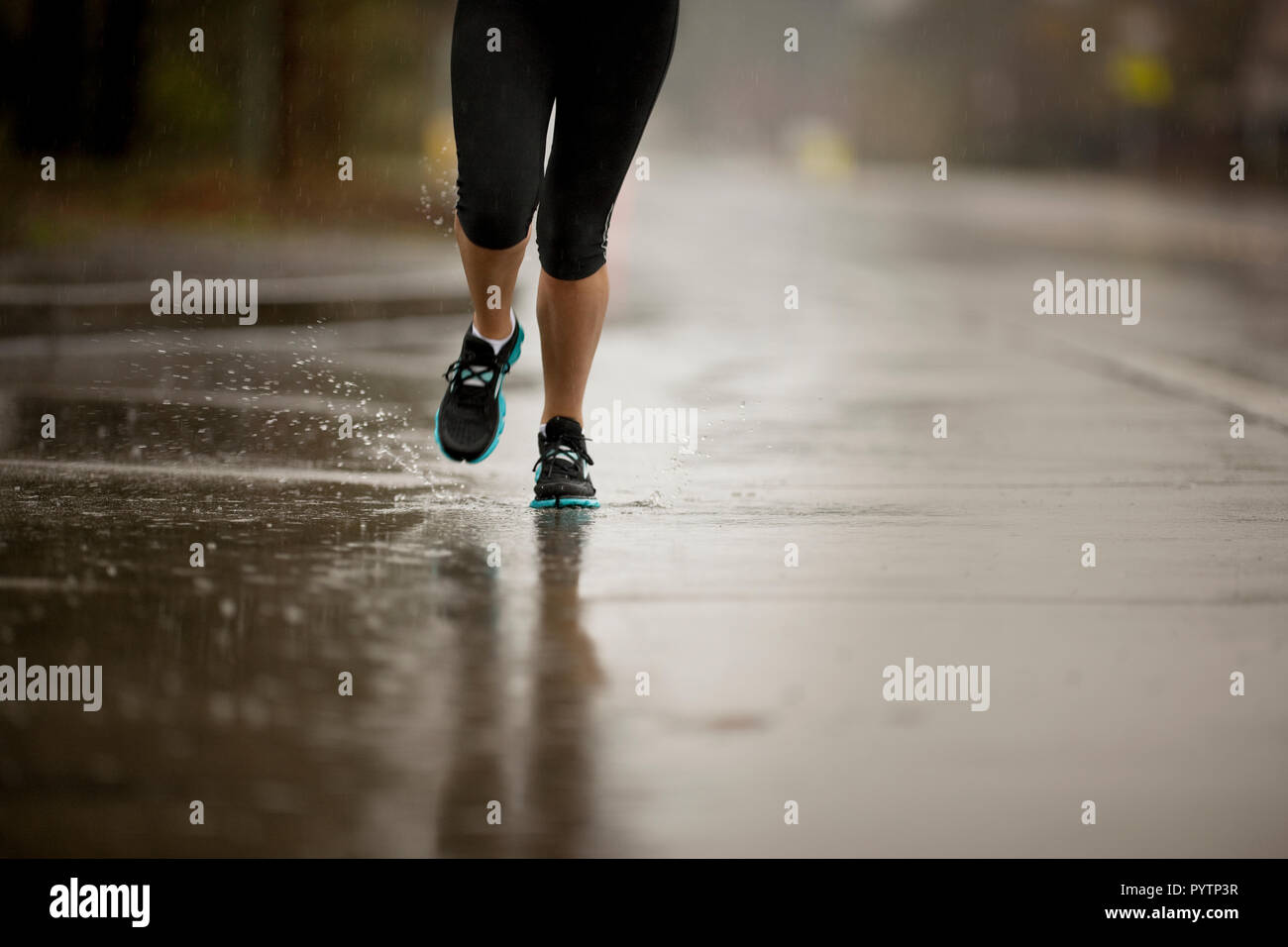 Young woman jogging on a residential street in the rain Stock Photo - Alamy