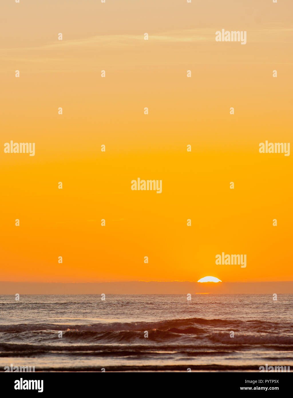 Sun setting over the ocean Stock Photo - Alamy