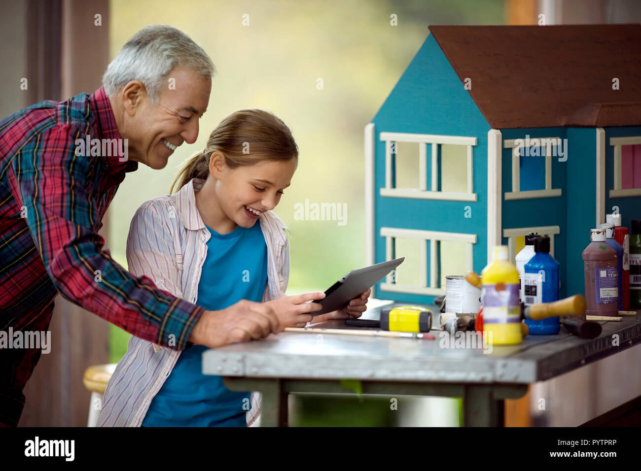 Smiling senior man and his granddaughter having fun looking at a iPad ...