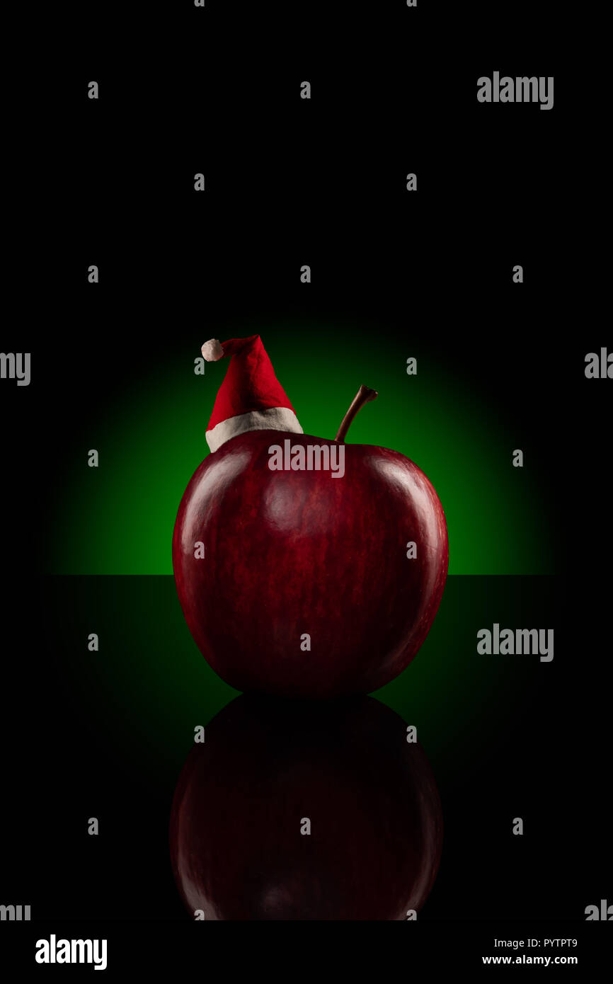 An apple wear Santa Claus hat isolated on reflective black board with ...