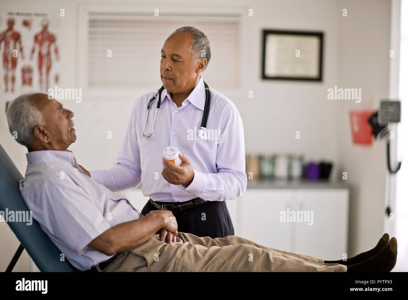 Male doctor having a conversation with a patient while holding a bottle ...