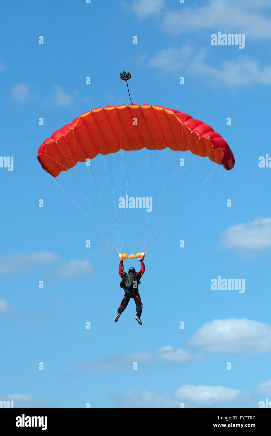 Parachutist floating to a red square-shaped parachute Stock Photo - Alamy