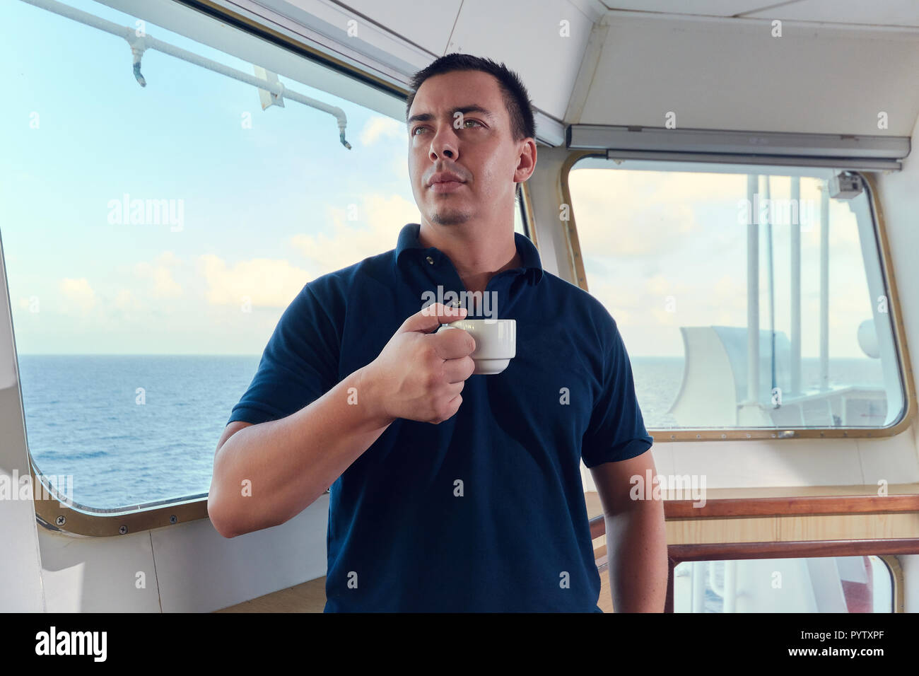 Navigation offcier / Pilot on the bridge of a ship underway with cup of ...