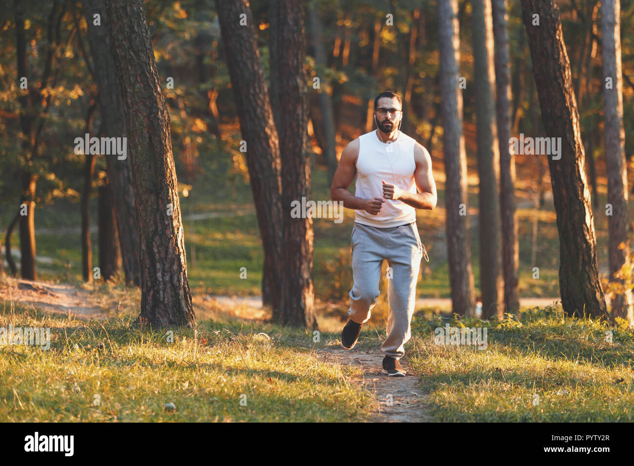 Multicultural handsome bearded man in sportswear jogging at the forest ...