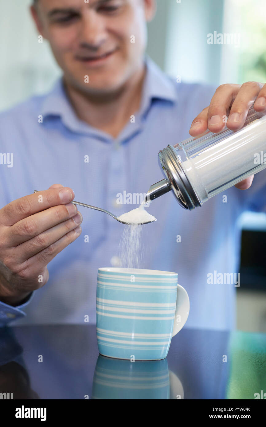 Mature Man Adding Sugar To Hot Drink At Home Stock Photo - Alamy