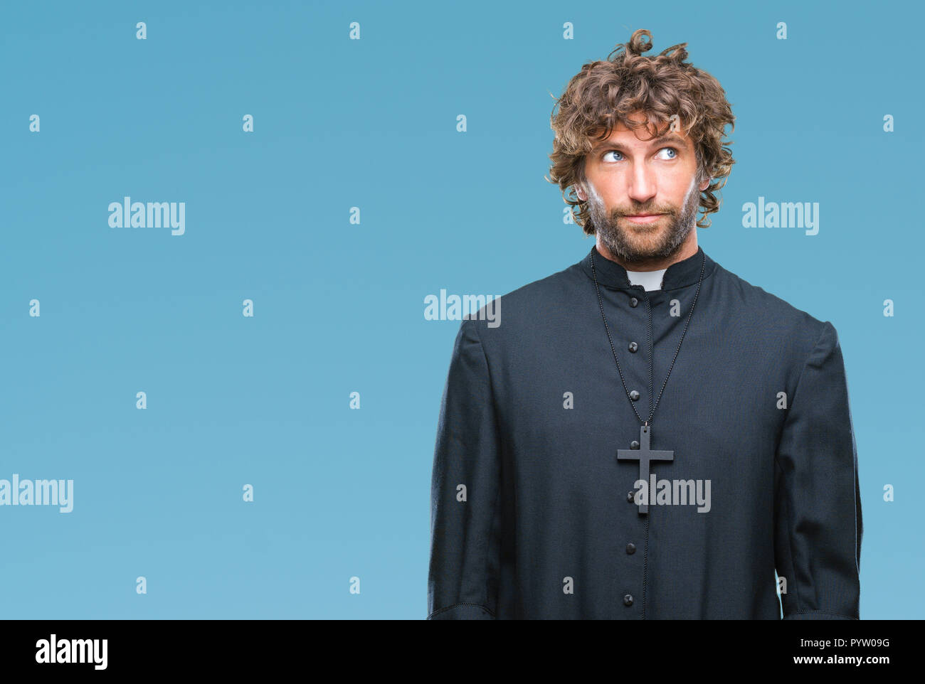 Handsome hispanic catholic priest man over isolated background smiling ...