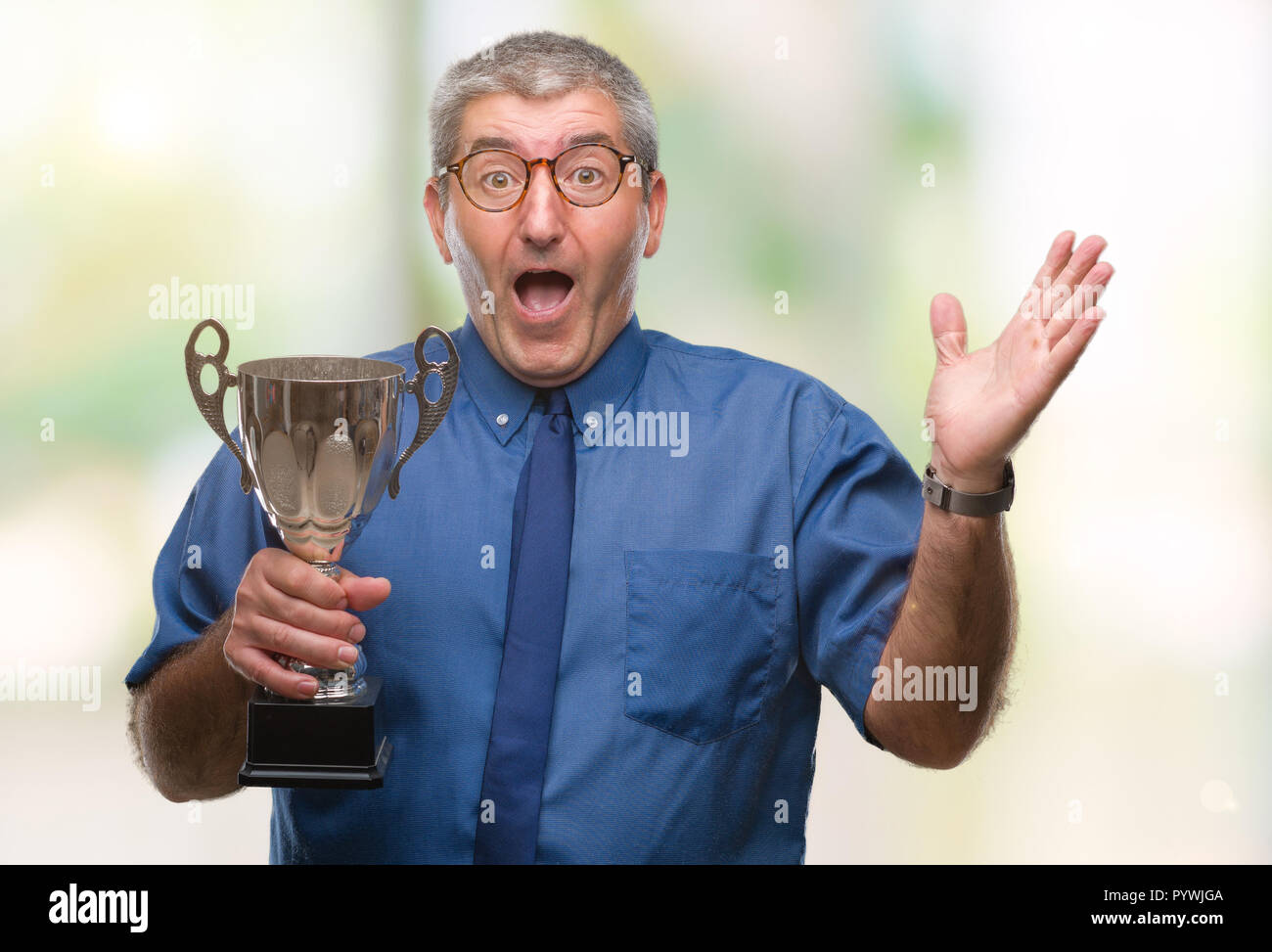 Handsome senior successful man holding trophy over isolated background ...