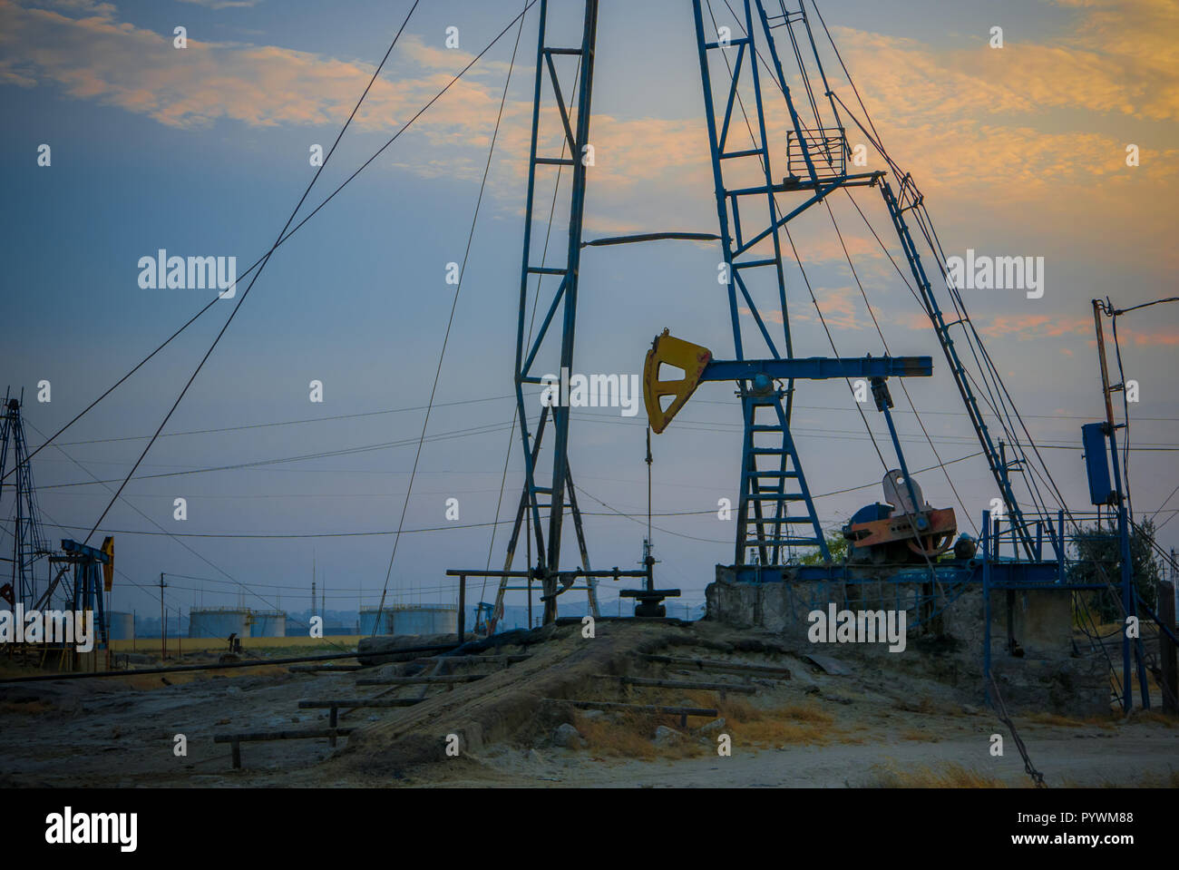 Petrol extraction, oilfield with petrol storage tanks in the background ...