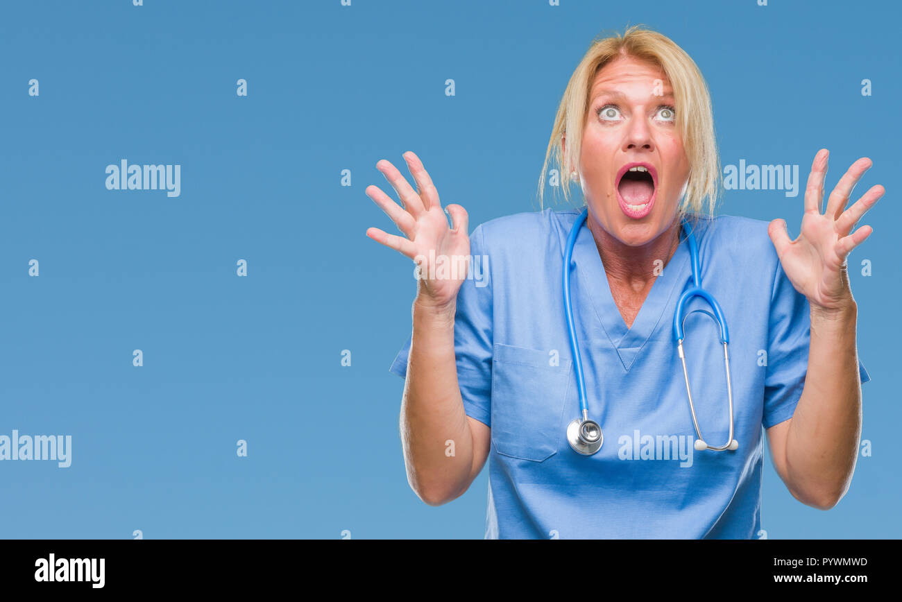 Middle age blonde nurse surgeon doctor woman over isolated background ...