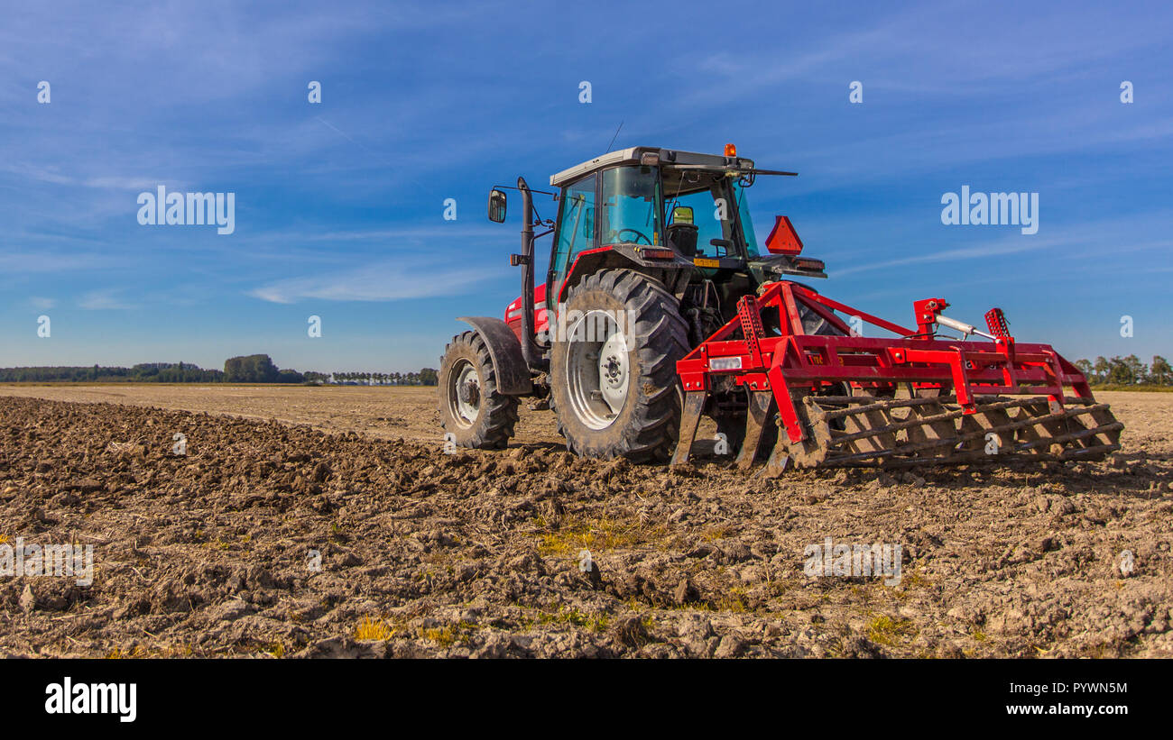 Field being ploughed by tractor under Blue Sky. Autumn Farming scene in ...