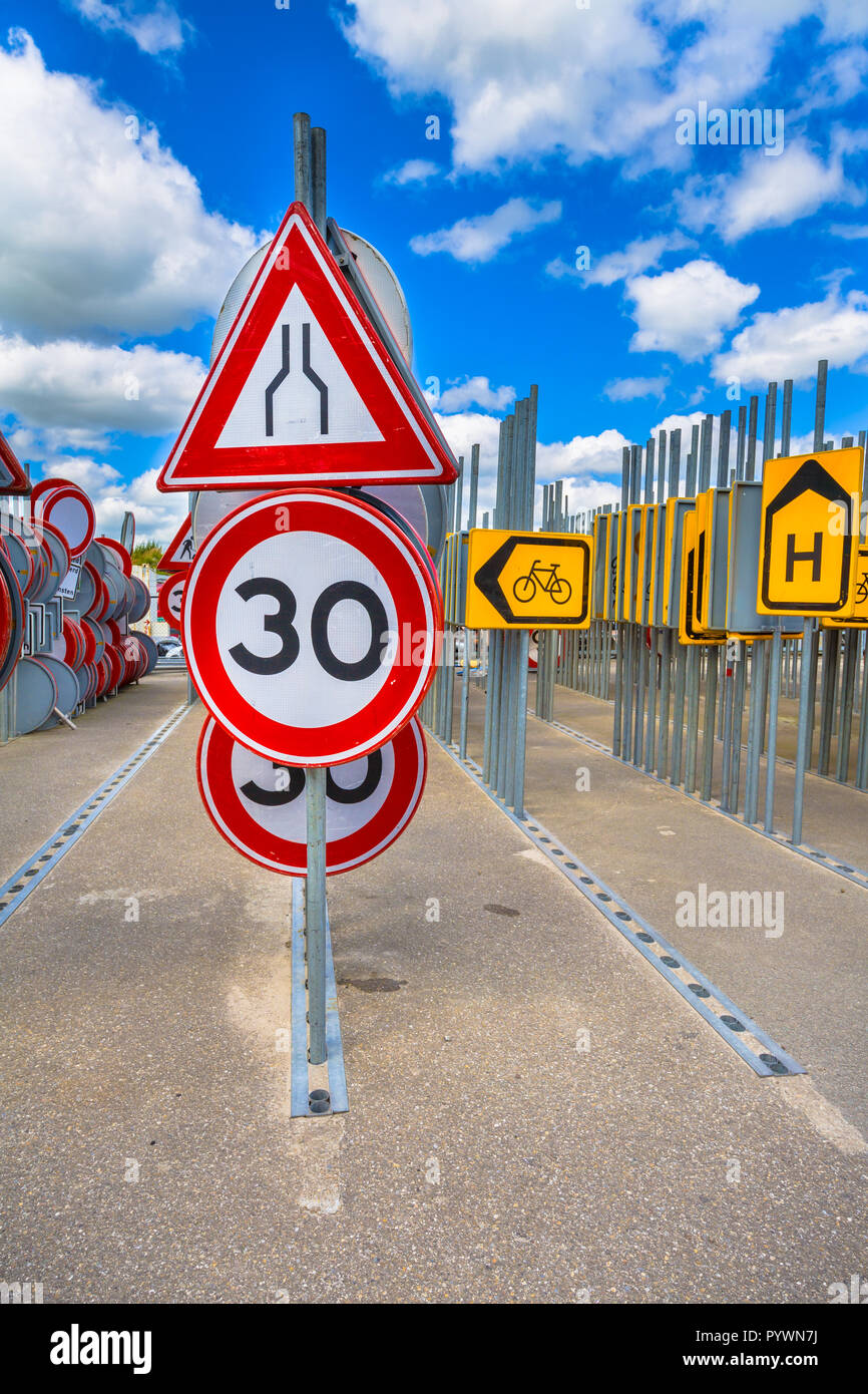 Bottleneck road narrowing sign and speed limit sign among other rows of ...
