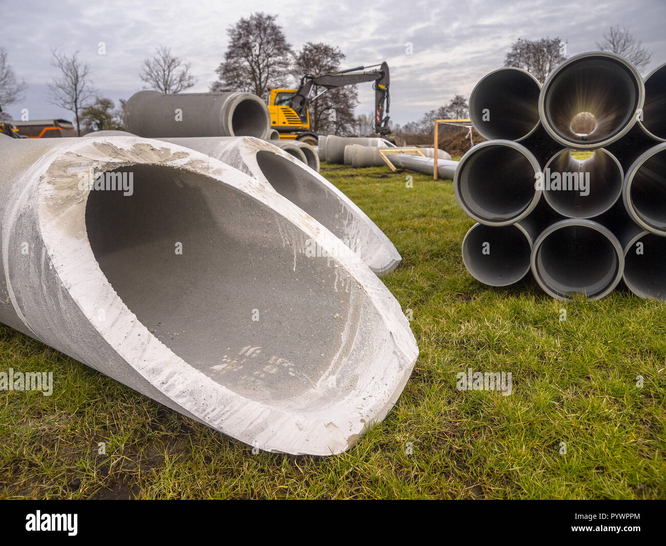 Concrete pipes and plastic draines with other building material on a ...