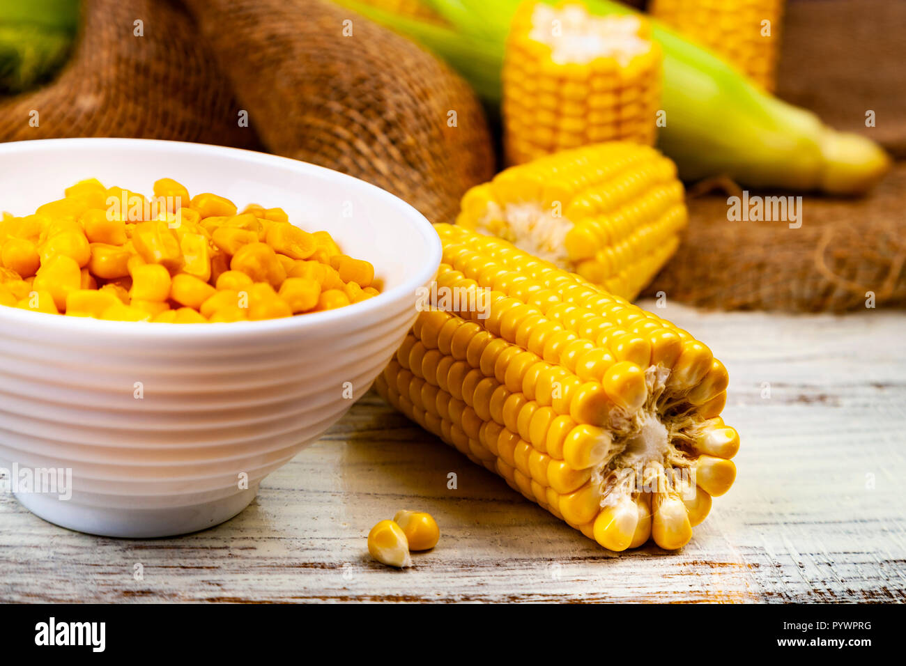 Ripe corn on a wooden table close-up. Raw and canned corn in a white ...