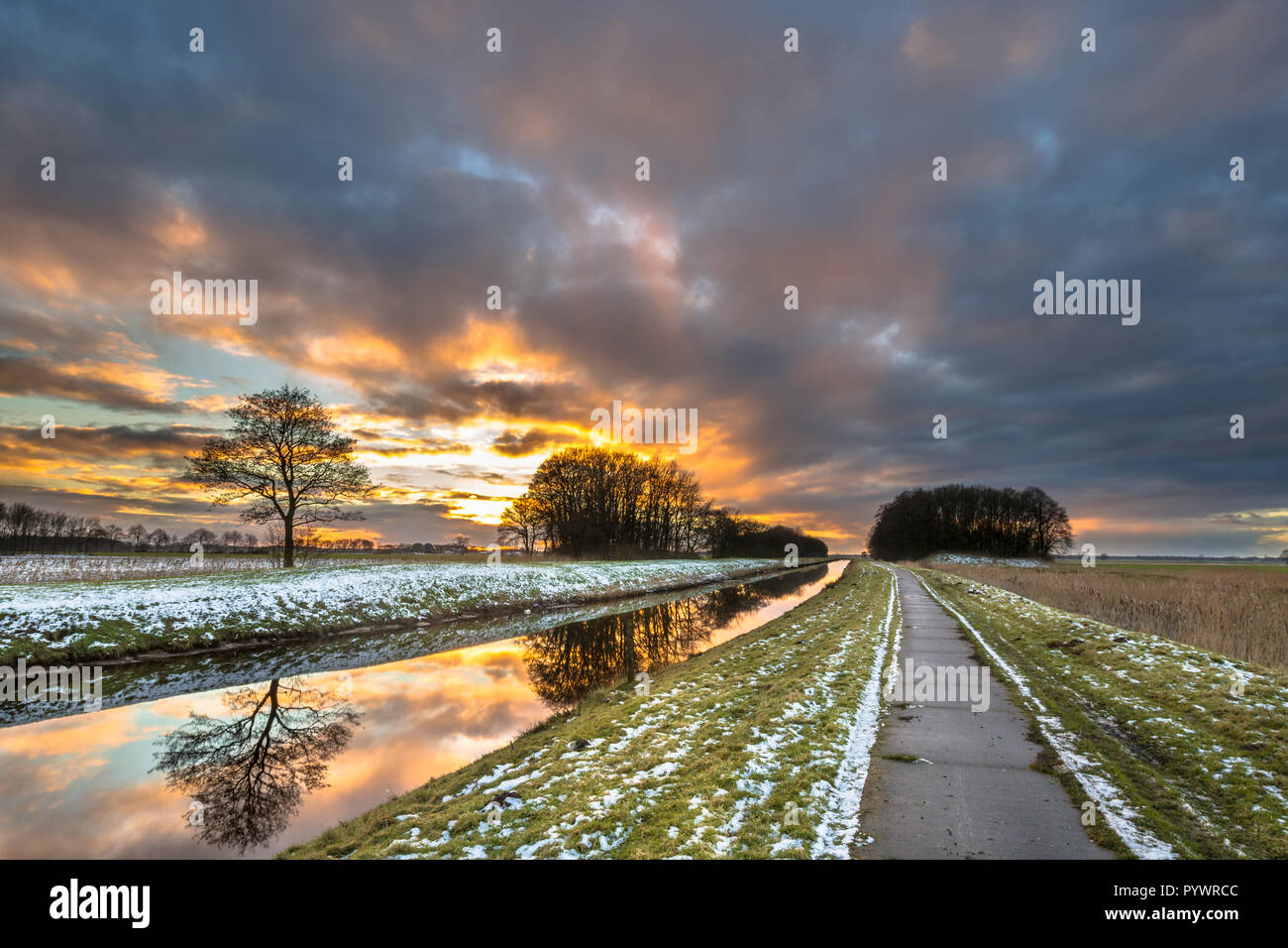 Lowland river Tjonger flowing through flat snowy countryside of Friesland in the Netherlands ...