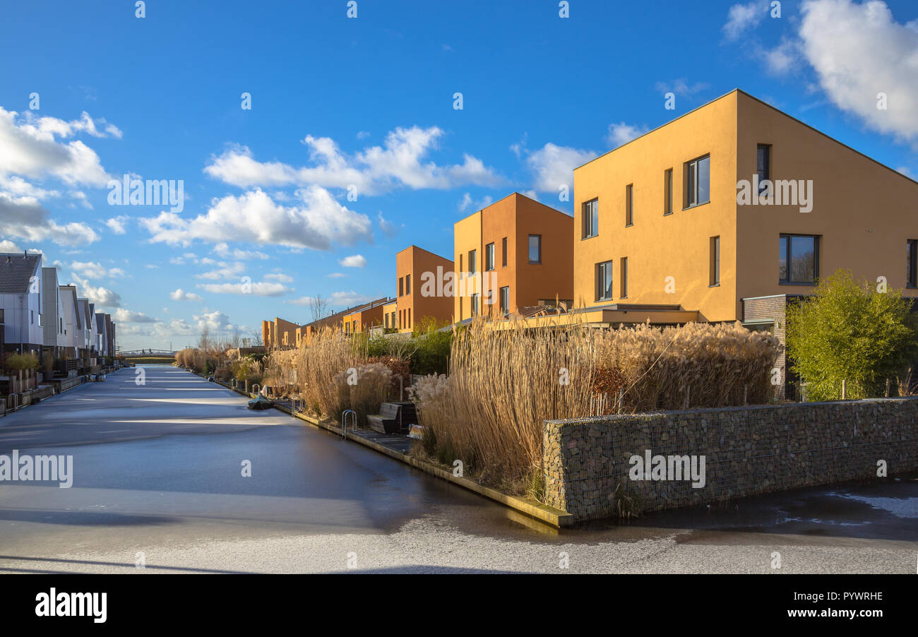 Modern futuristic family houses along a canal in winter setting with ...