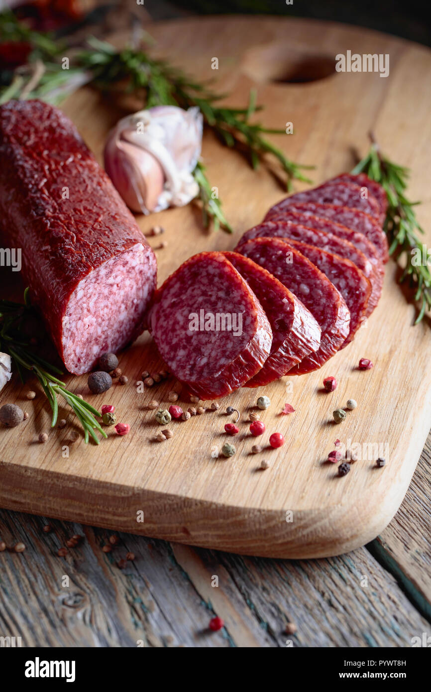 Smoked salami on a old wooden table. Sausages with rosemary , garlic ...