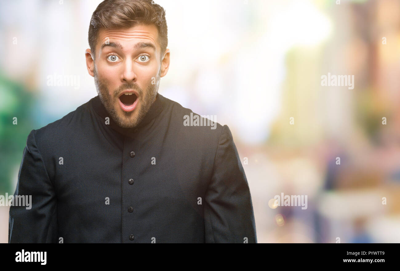 Young catholic christian priest man over isolated background afraid and ...