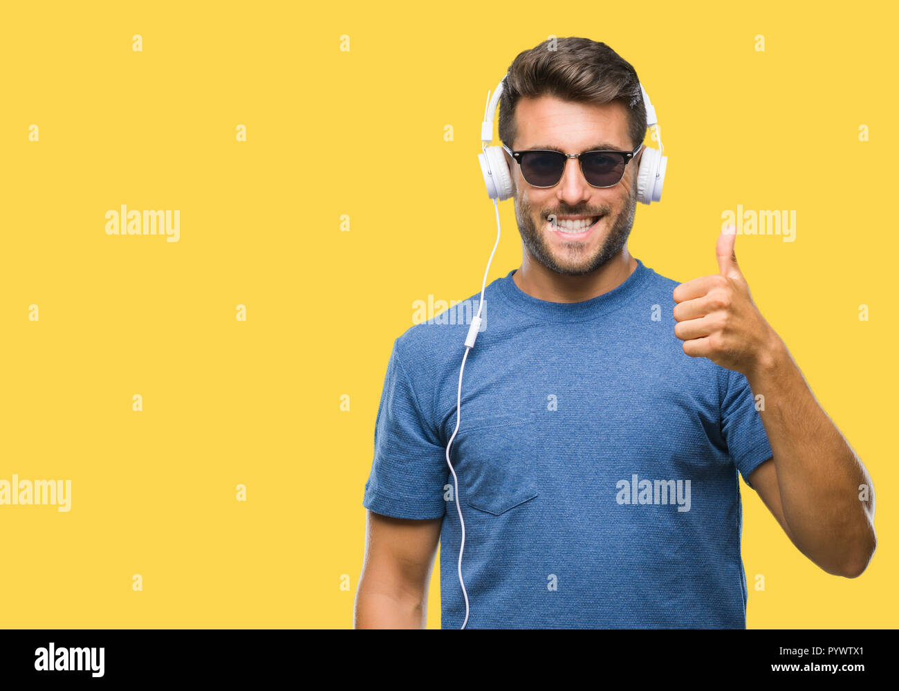 Young handsome man wearing headphones listening to music over isolated background doing happy ...