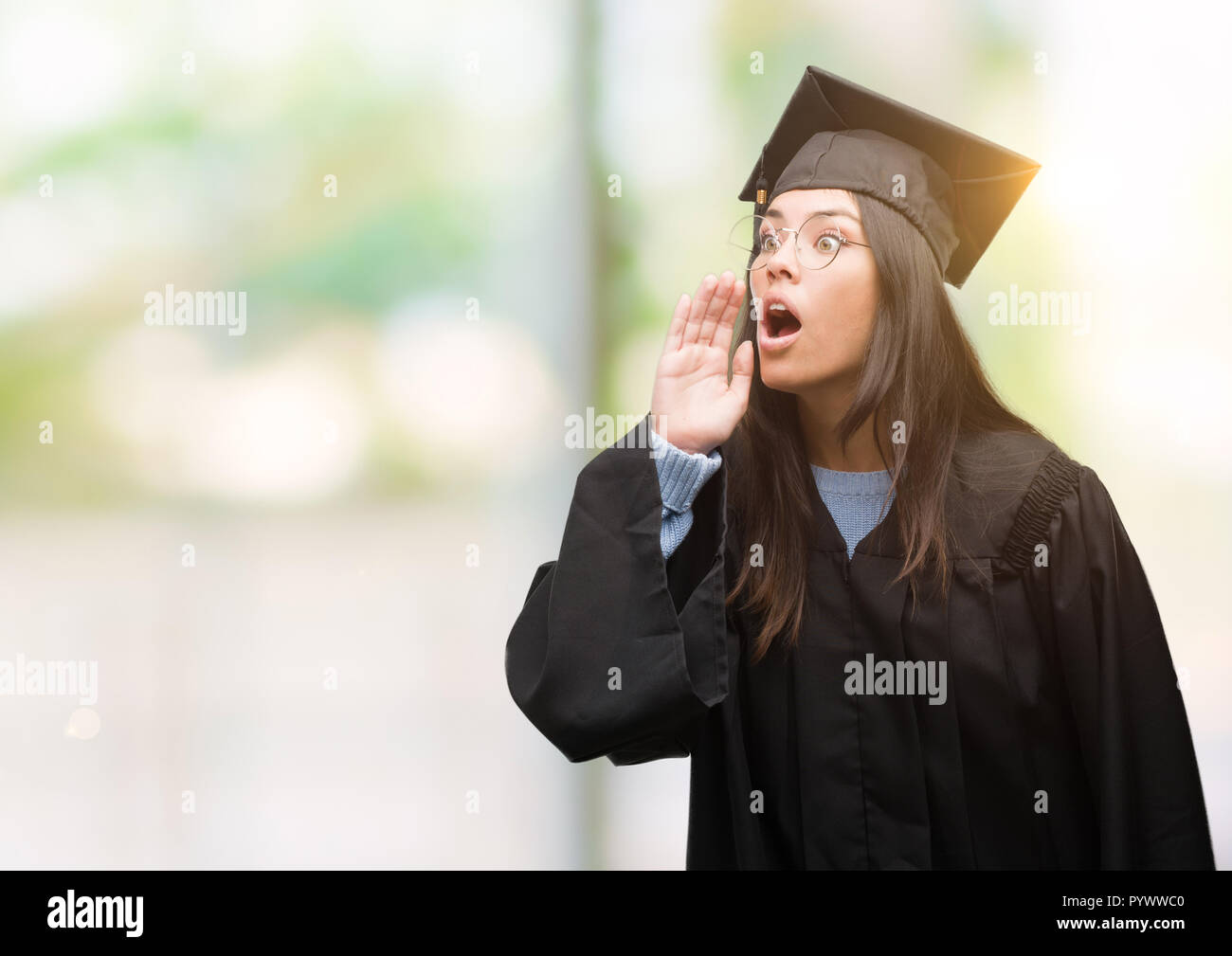 Young hispanic woman wearing graduated cap and uniform shouting and ...