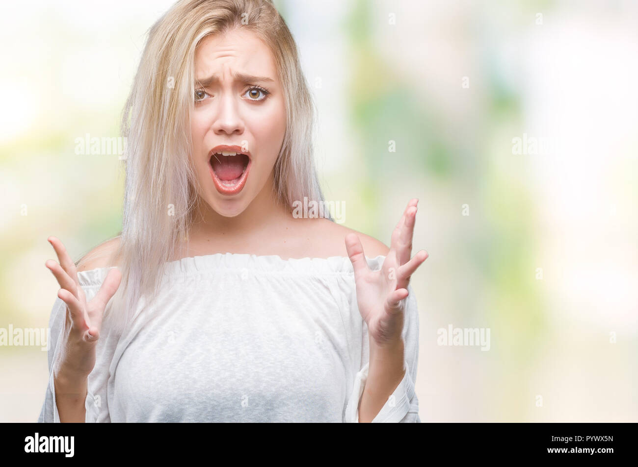 Young blonde woman over isolated background crazy and mad shouting and ...