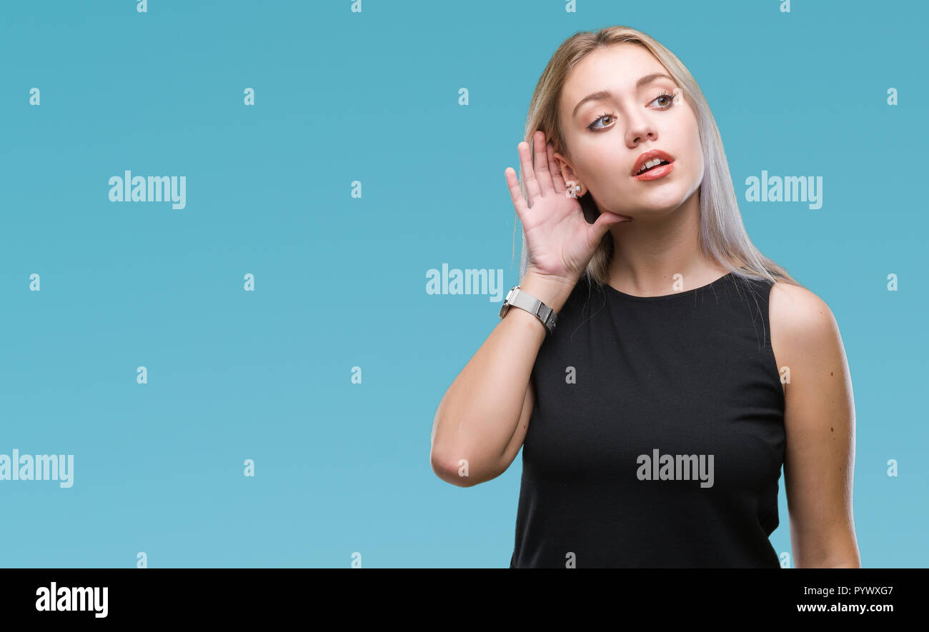 Young blonde woman over isolated background smiling with hand over ear ...