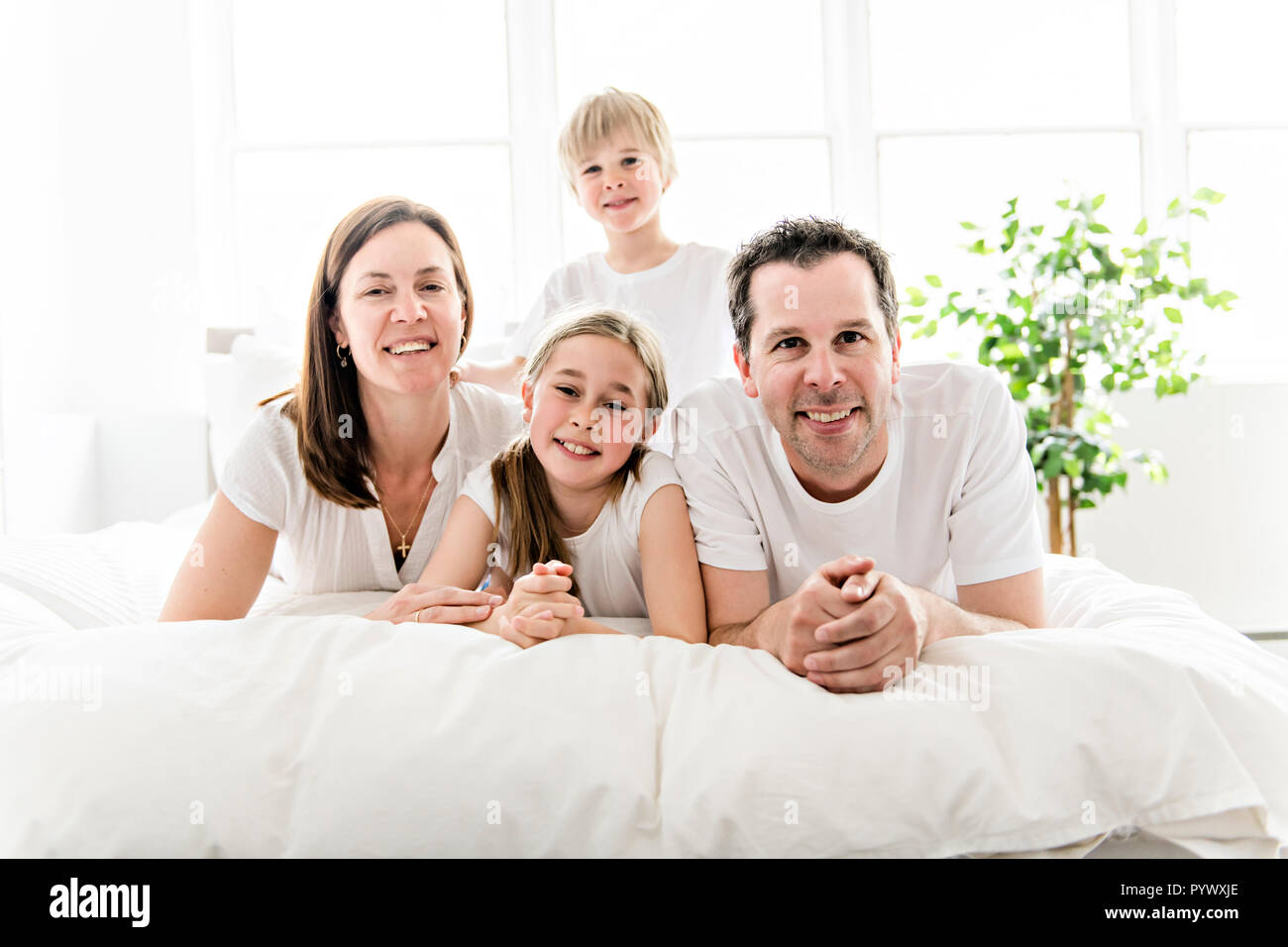 A Family of four having fun on the bed at home Stock Photo - Alamy