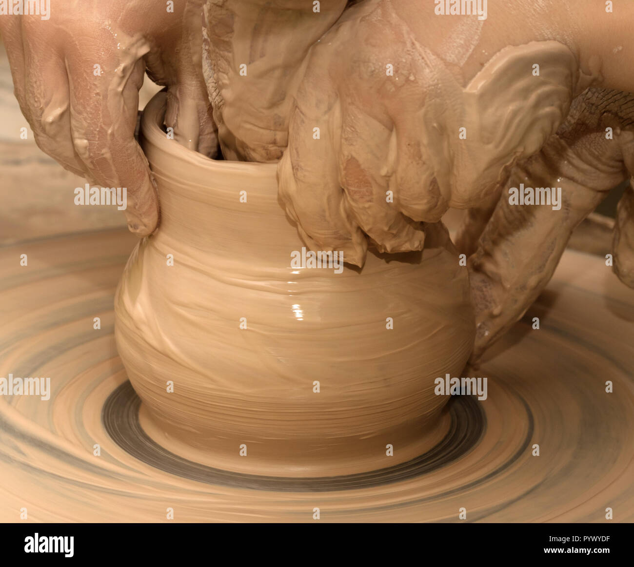 Hands of beginner and teacher in process of making clay bowl on pottery ...