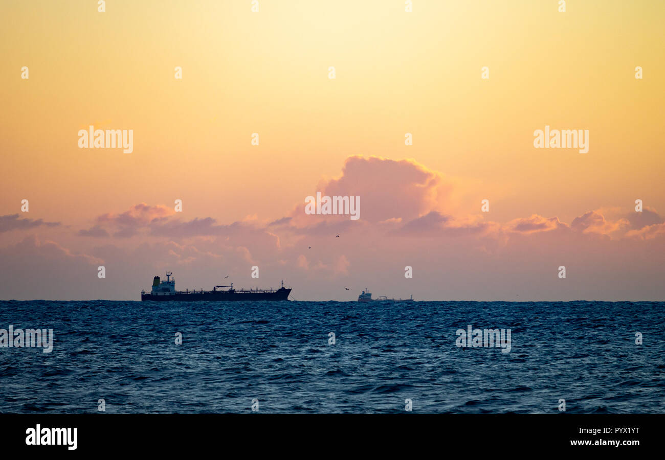 A cruise ship is seen at the horizon line in the sea, before sunset ...
