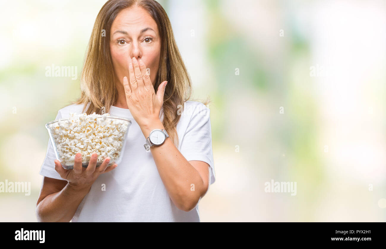 Middle age hispanic woman eating popcorn over isolated background cover ...