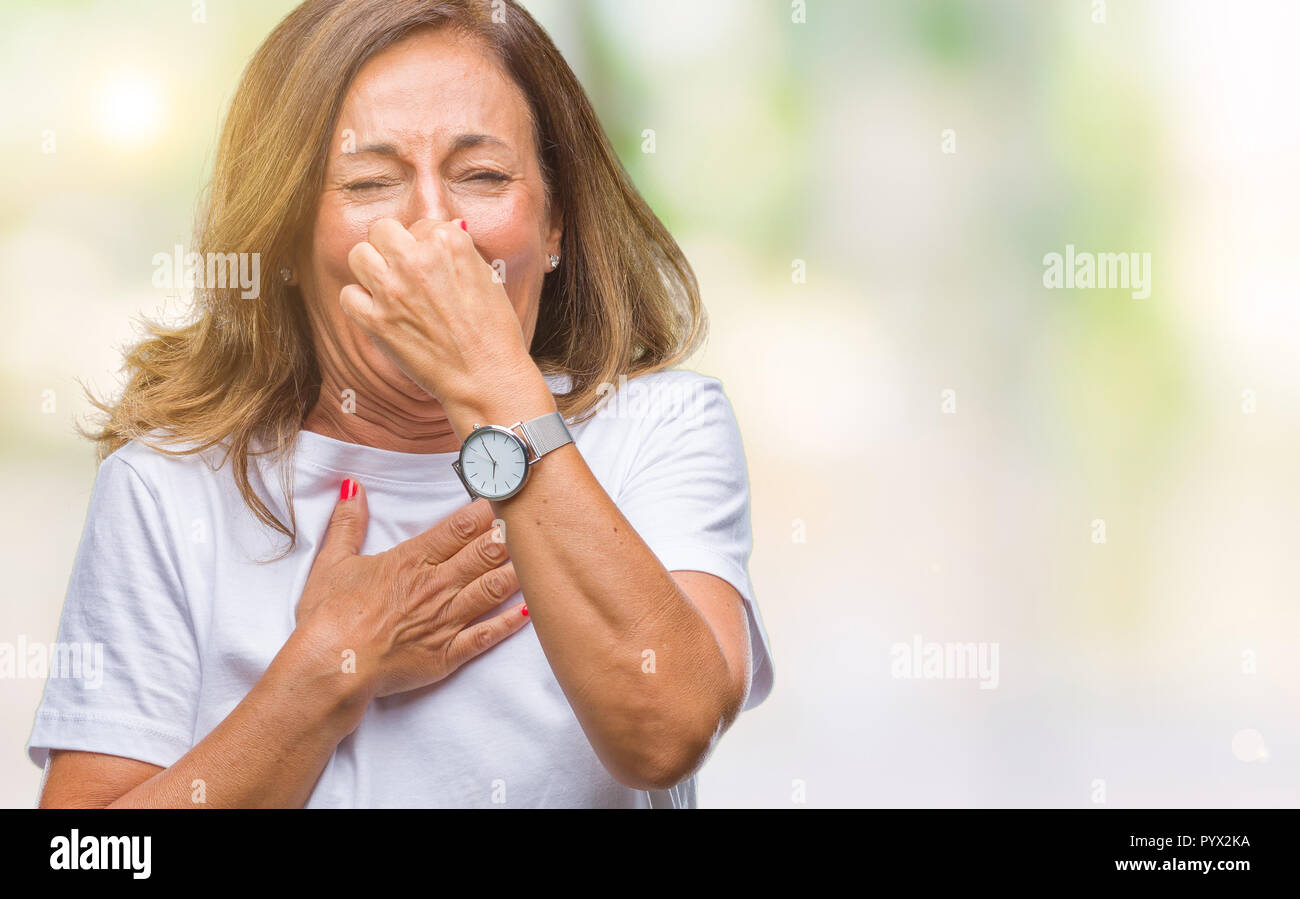 Middle age senior hispanic woman over isolated background smelling ...