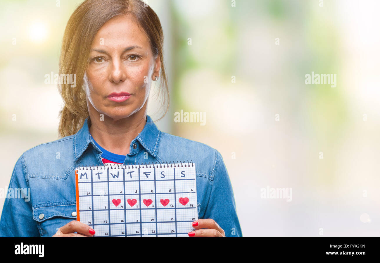 Middle age senior hispanic woman holding menstruation calendar over ...