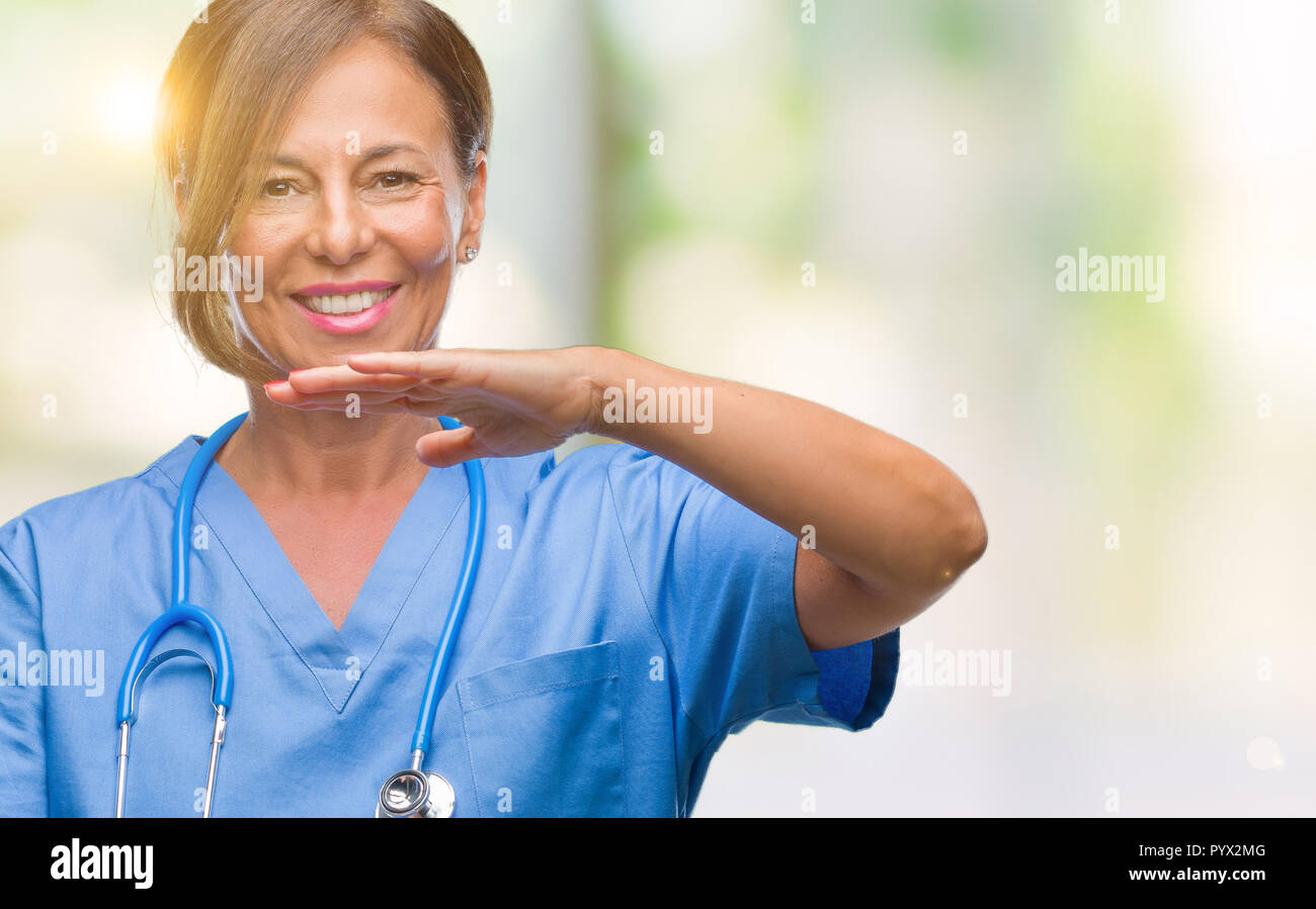 Middle age senior nurse doctor woman over isolated background gesturing ...