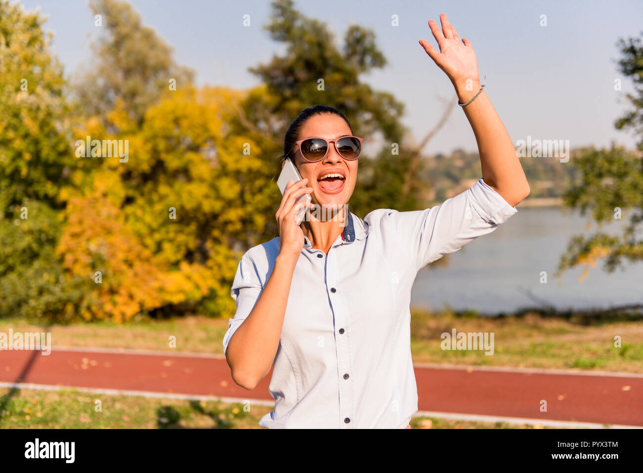 Portrait of young woman using mobile phone in the park by river Stock ...
