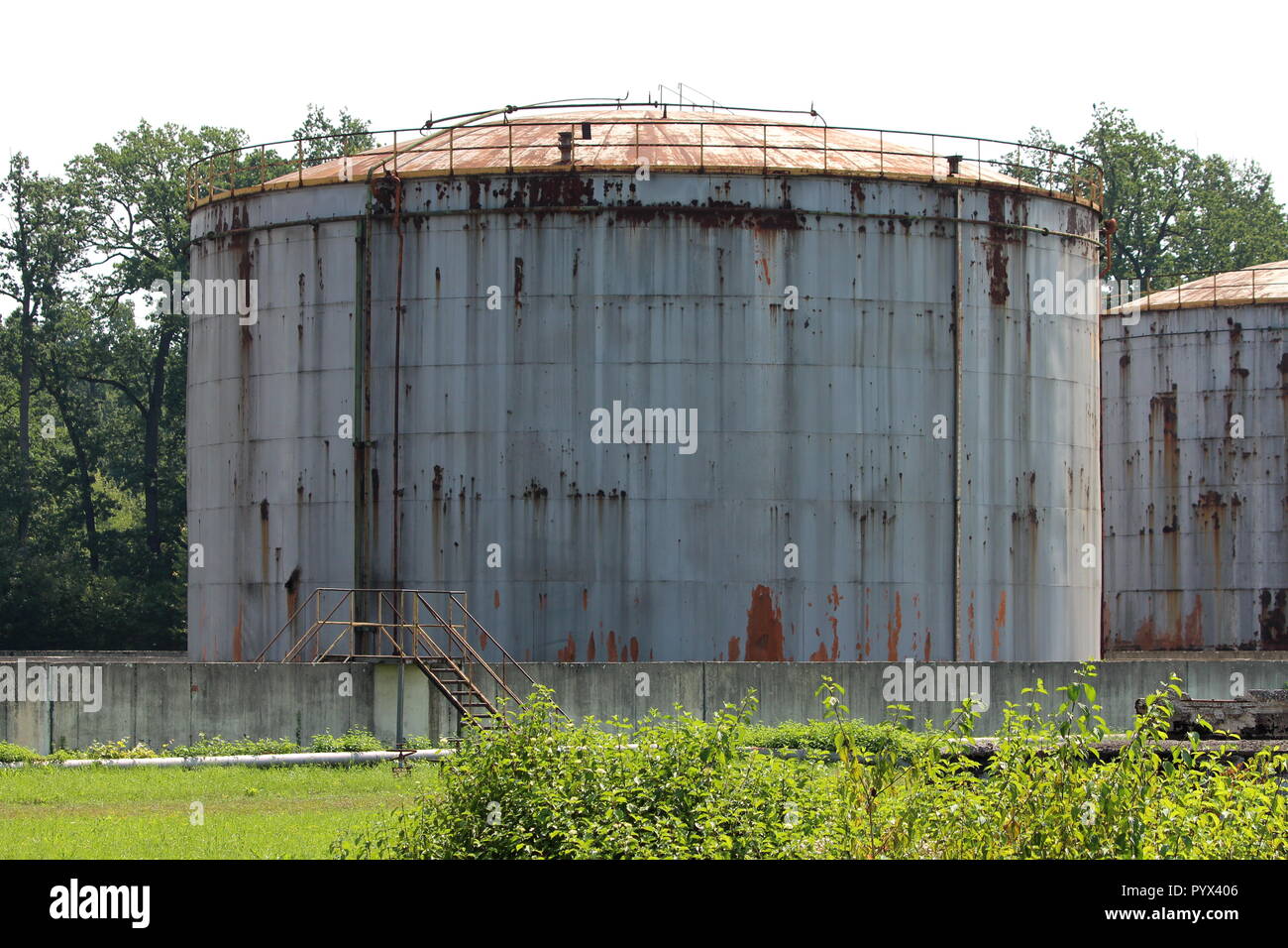 Large metal rusted storage silo surrounded with rusted metal bridge ...