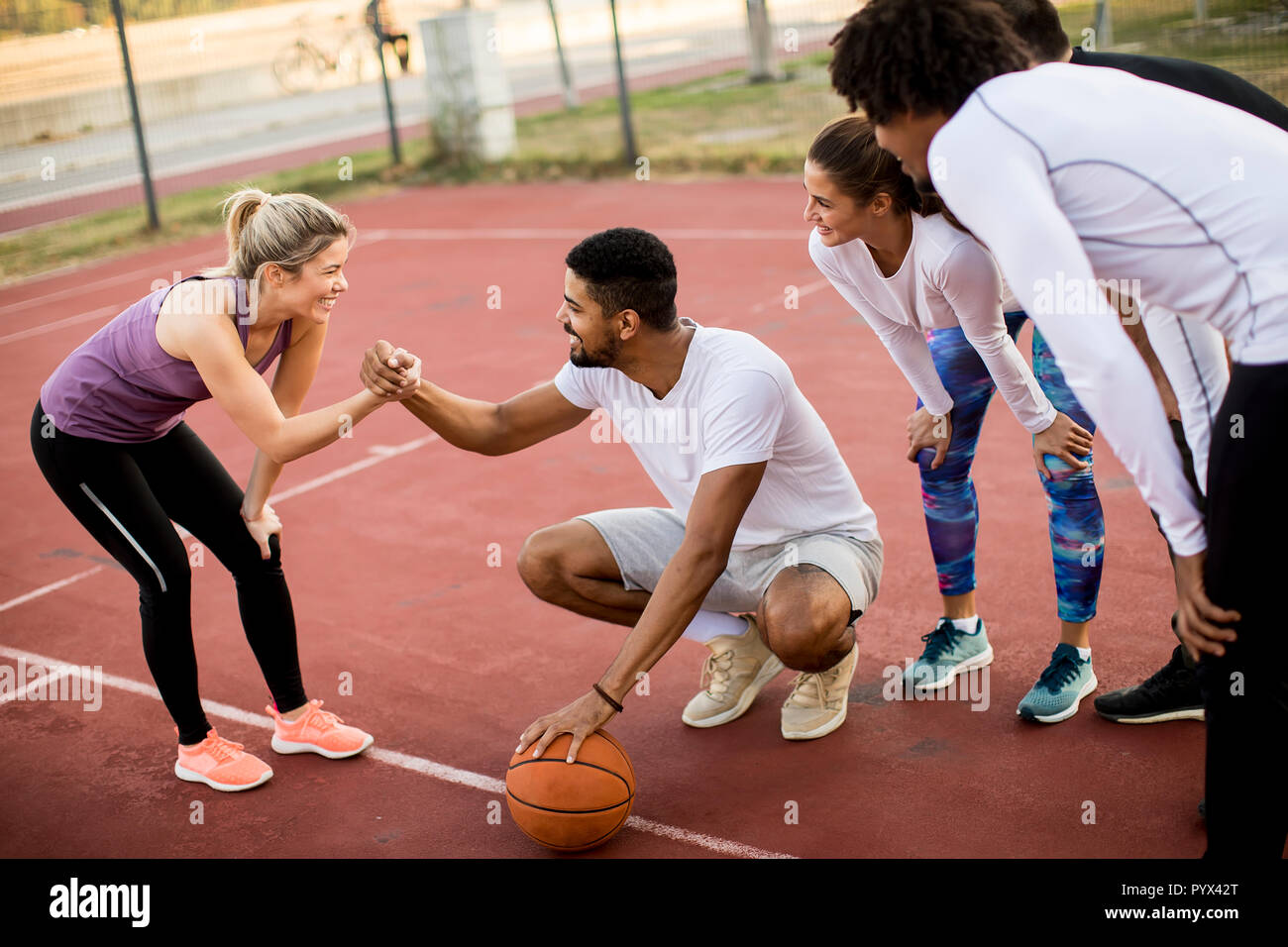Group of multiethnic young people playing basketball on court Stock ...