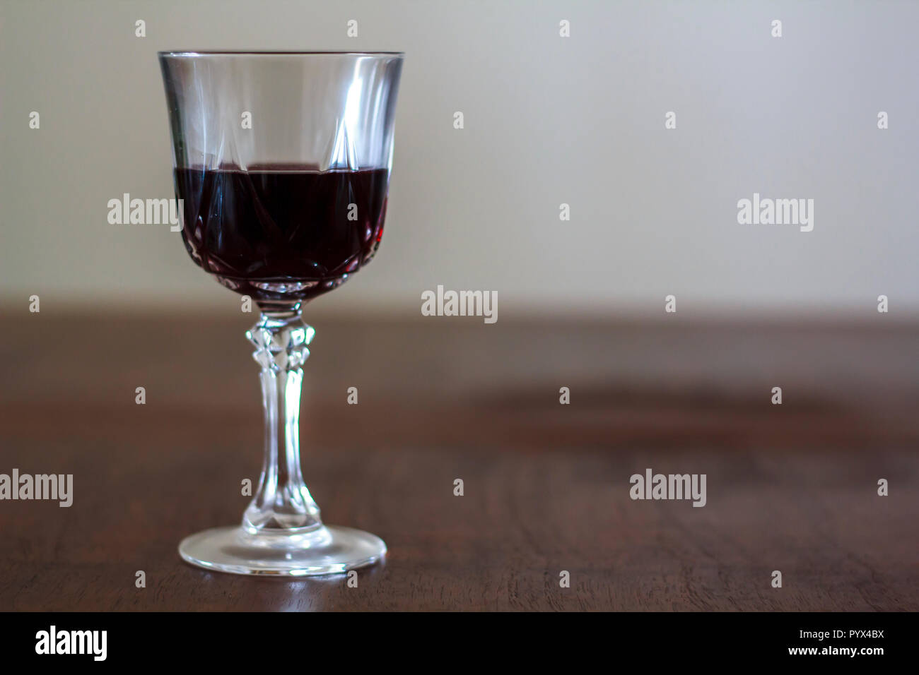 Glass of wine under wooden table Stock Photo - Alamy