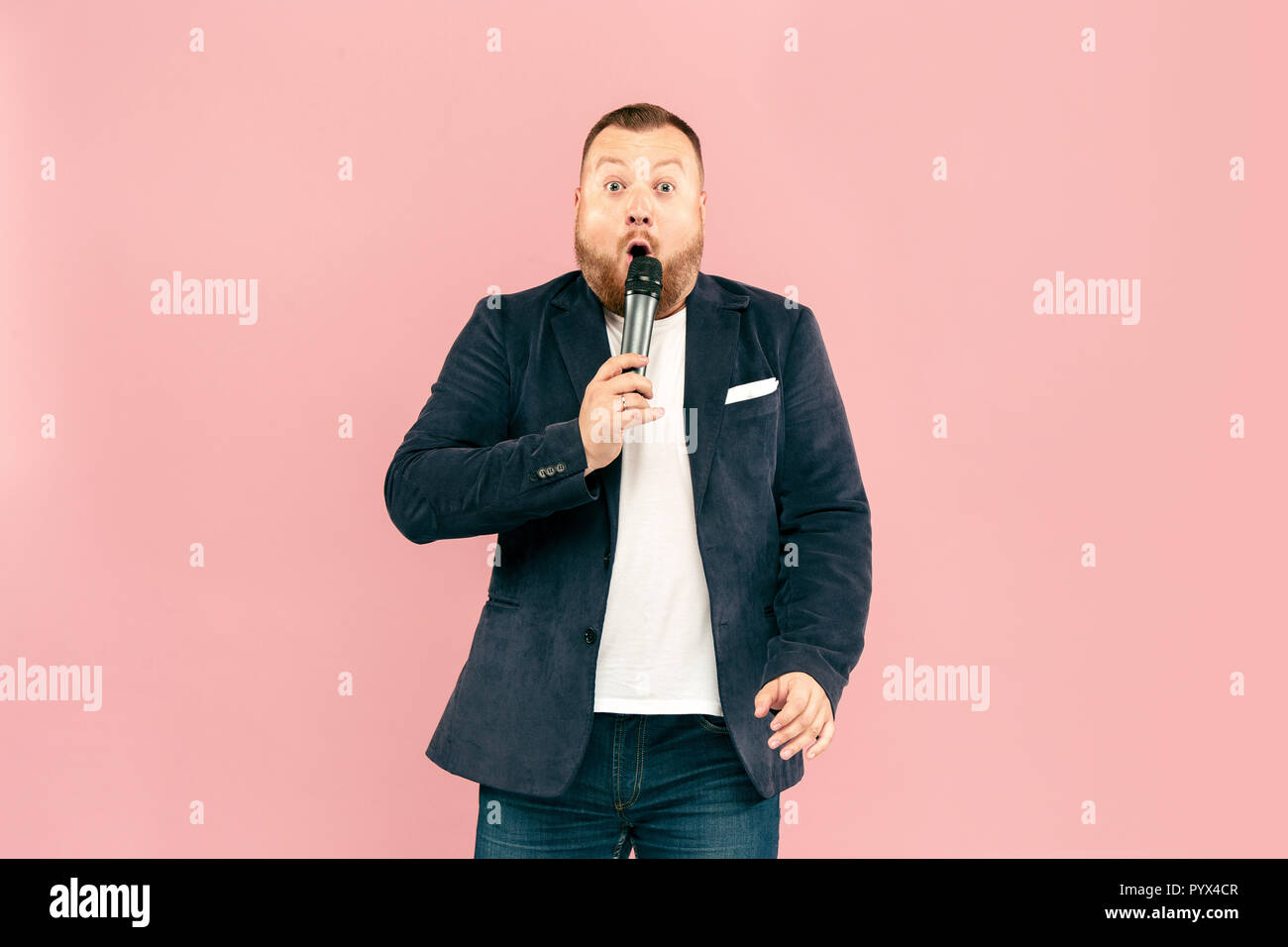 Young man with microphone on pink background, leading with microphone ...