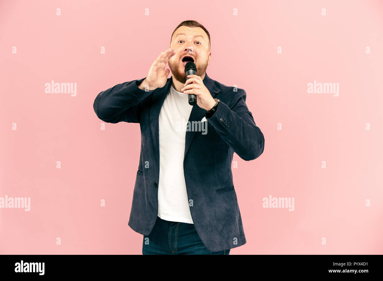 Young man with microphone on pink background, leading with microphone ...