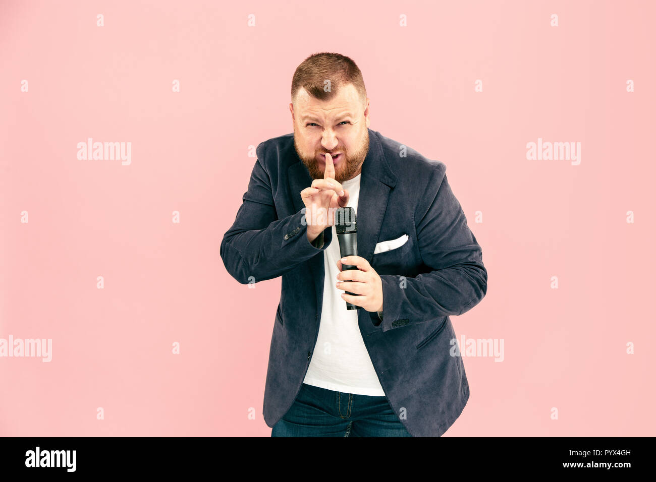 Young man with microphone on pink background, leading with microphone ...