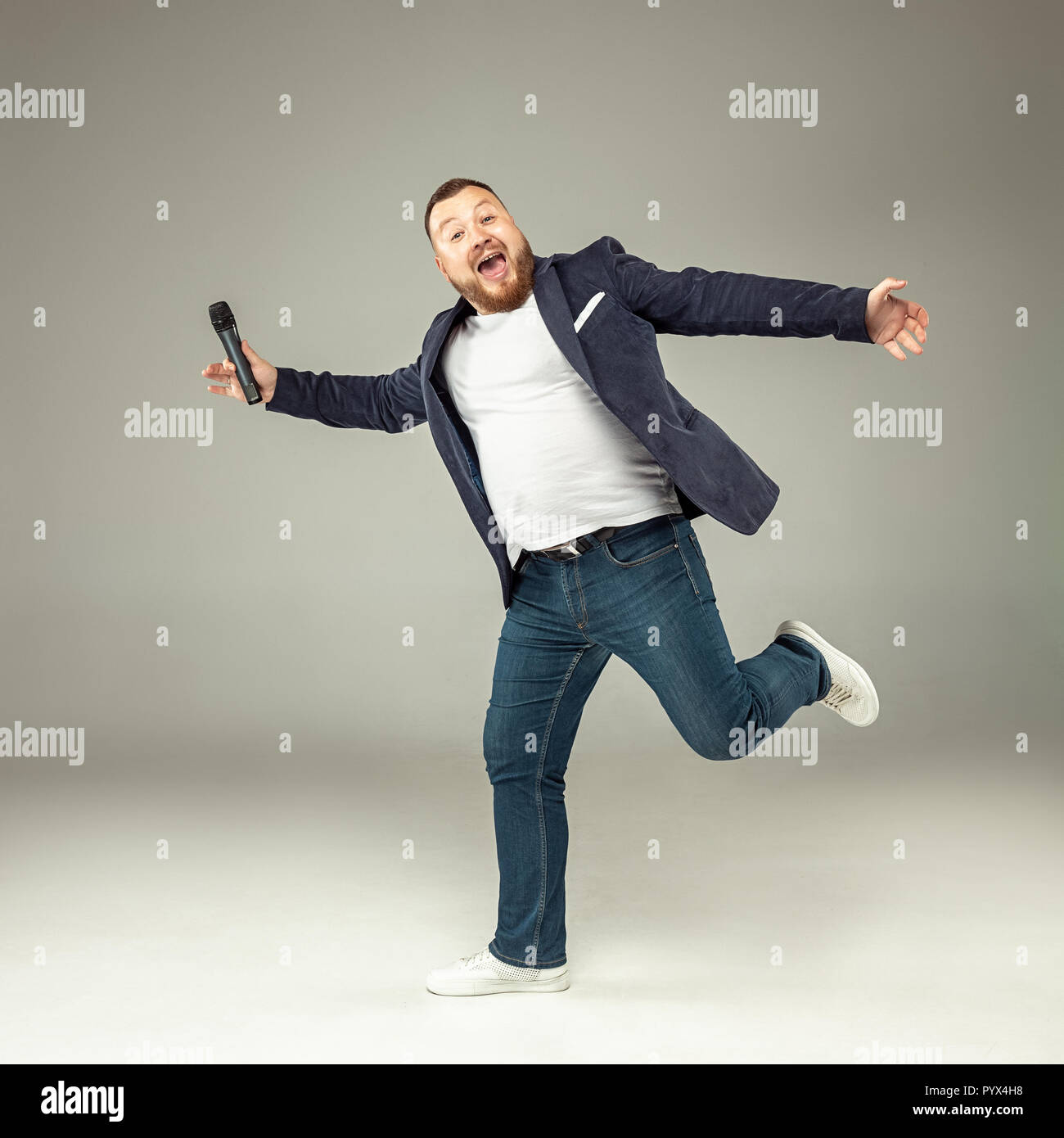 Young man with microphone on gray background, leading with microphone ...