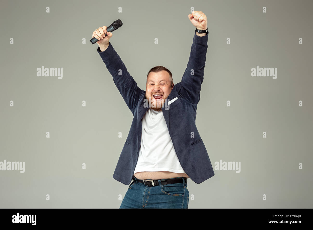 Young man with microphone on gray background, leading with microphone ...