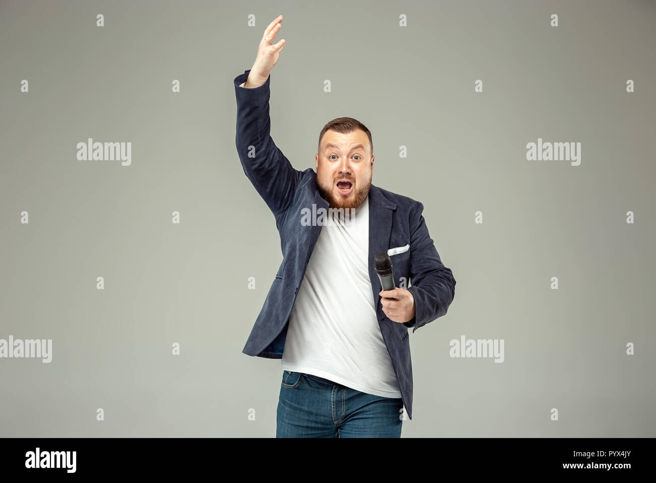 Young man with microphone on gray background, leading with microphone ...