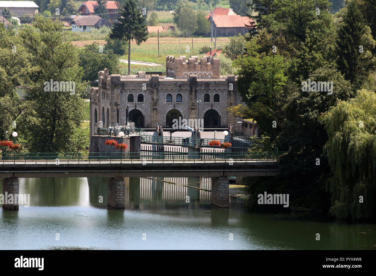 Stone bridge with old lamp posts and flowers in front of old dam ...