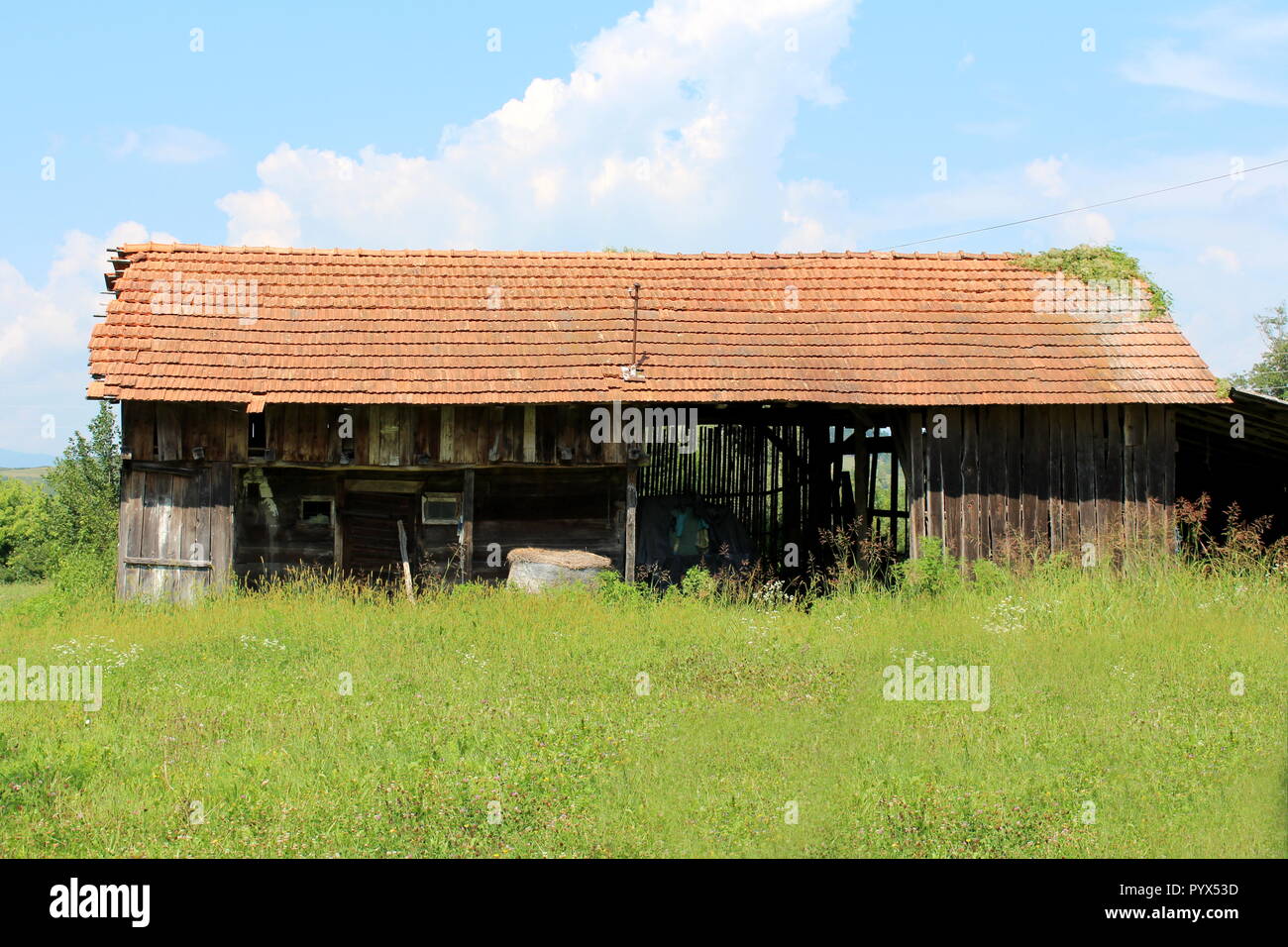 Unused abandoned wooden barn with open space in middle and dilapidated ...