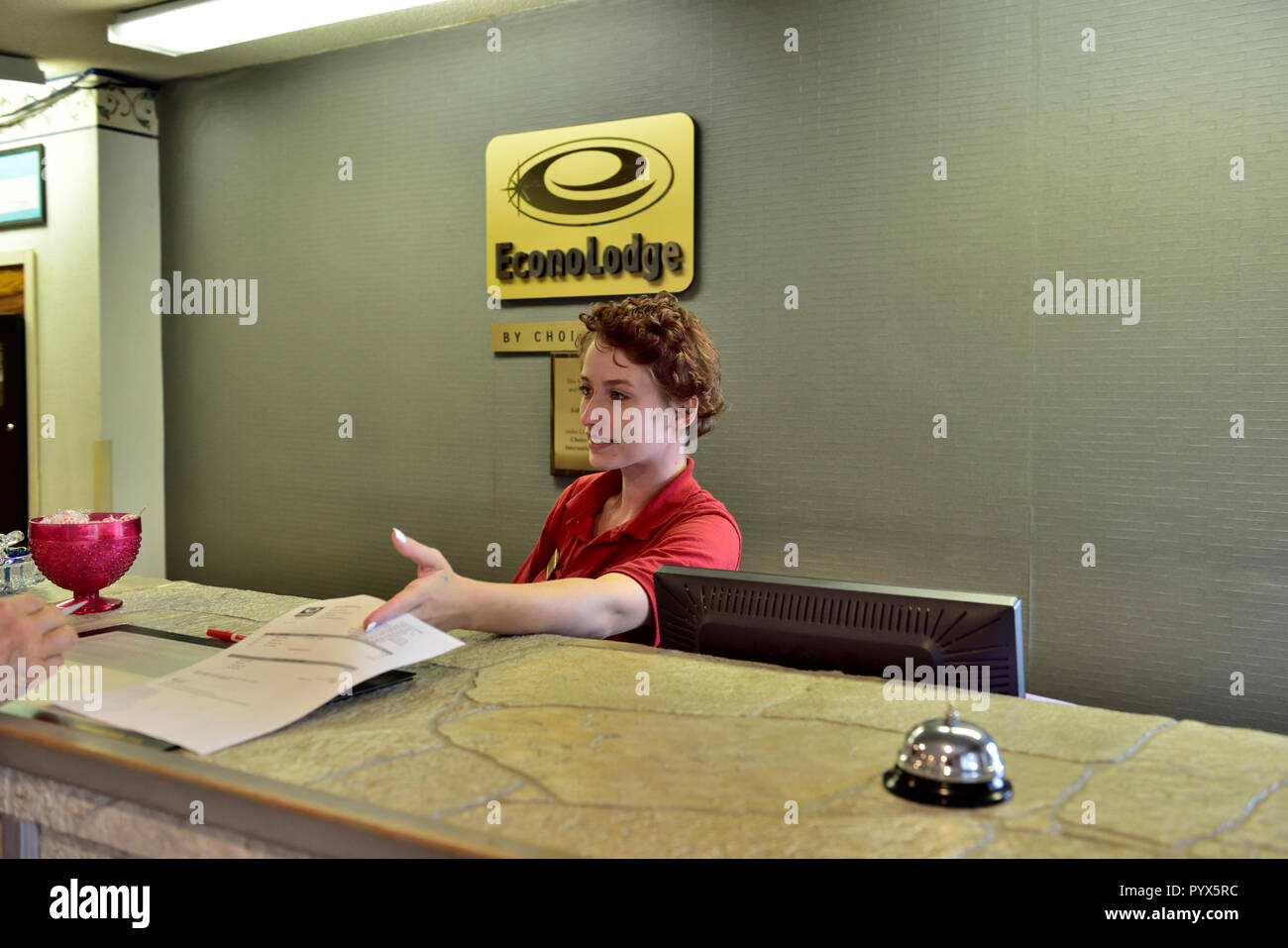 Young woman motel receptionist giving receipt to customer, Econo Lodge ...