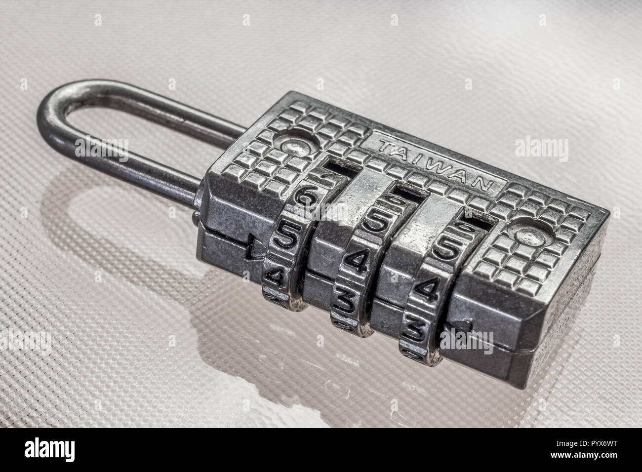 A closeup of a metallic numbered password lock over a reflecting ...