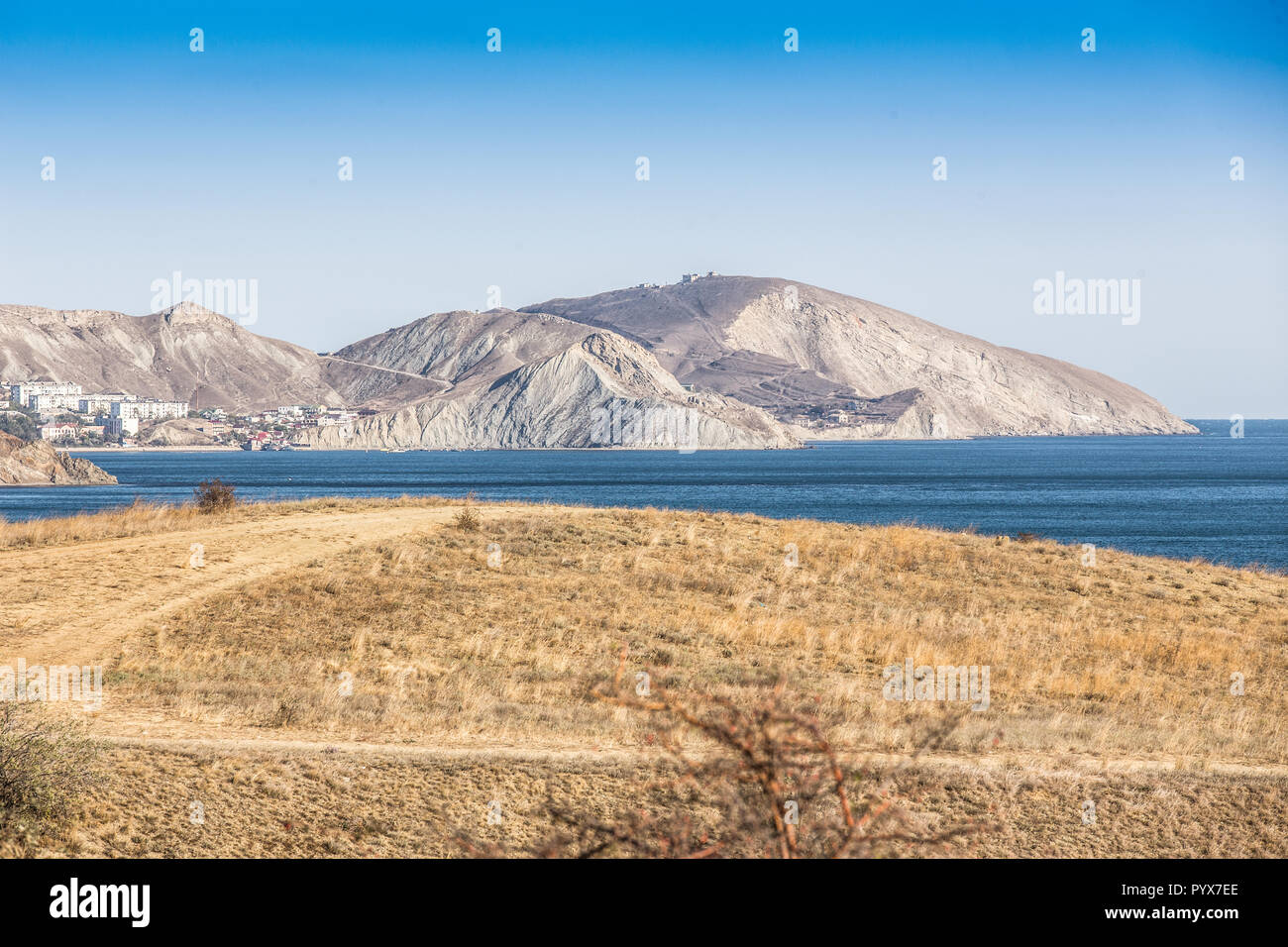 Sea bay surrounded with mountain range. Field in the front view. Houses ...