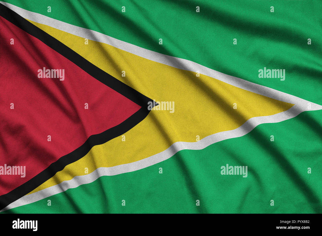 Guyana flag is depicted on a sports cloth fabric with many folds. Sport ...