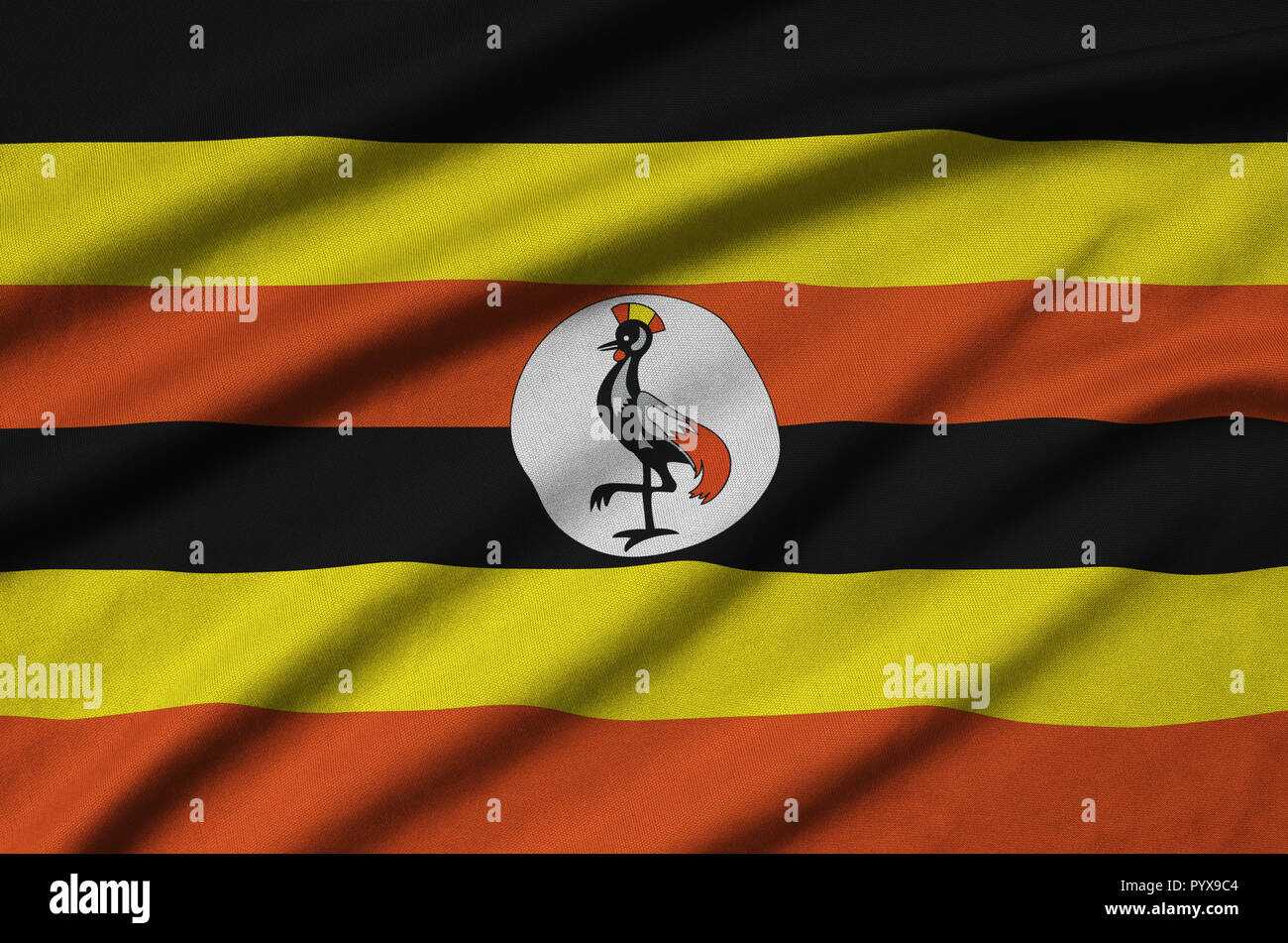 Uganda flag is depicted on a sports cloth fabric with many folds. Sport ...